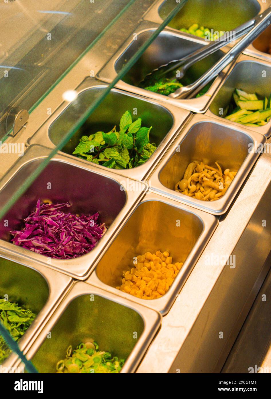 A colorful salad bar with various vegetables in metal containers. The ...