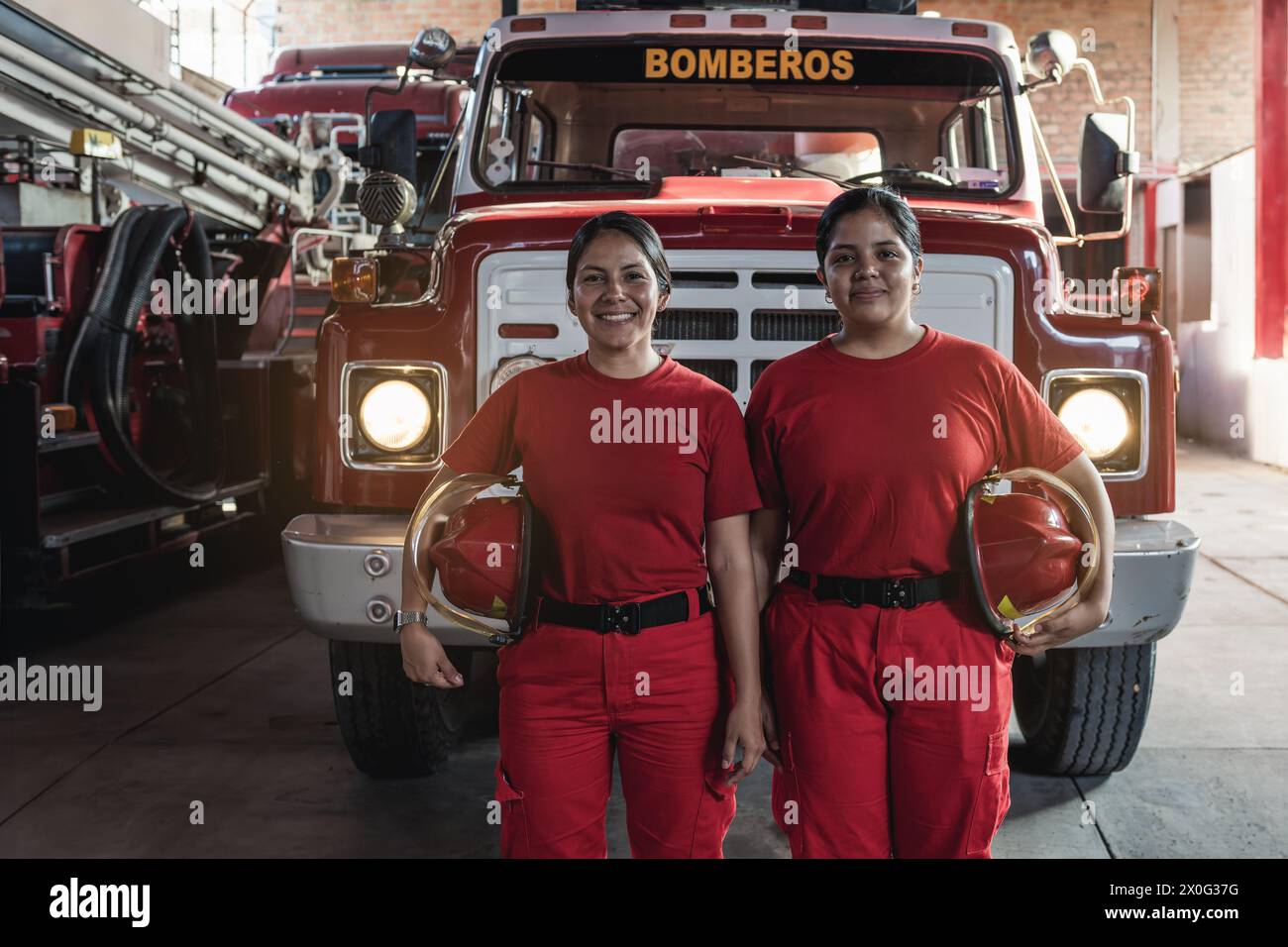 Portrait of happy female firefighters standing against fire engine ...