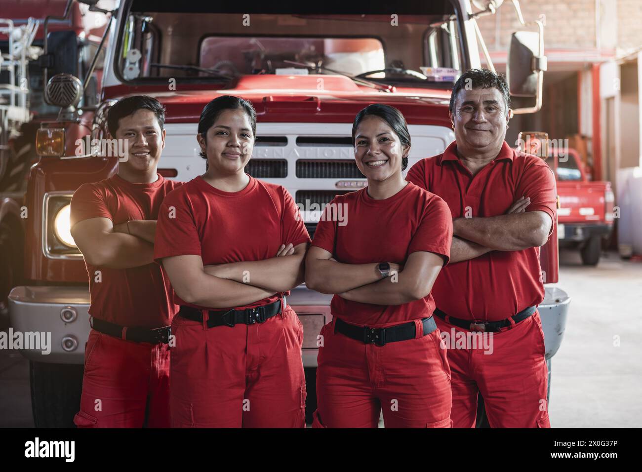 Smiling team of male and female firefighters at fire station Stock ...