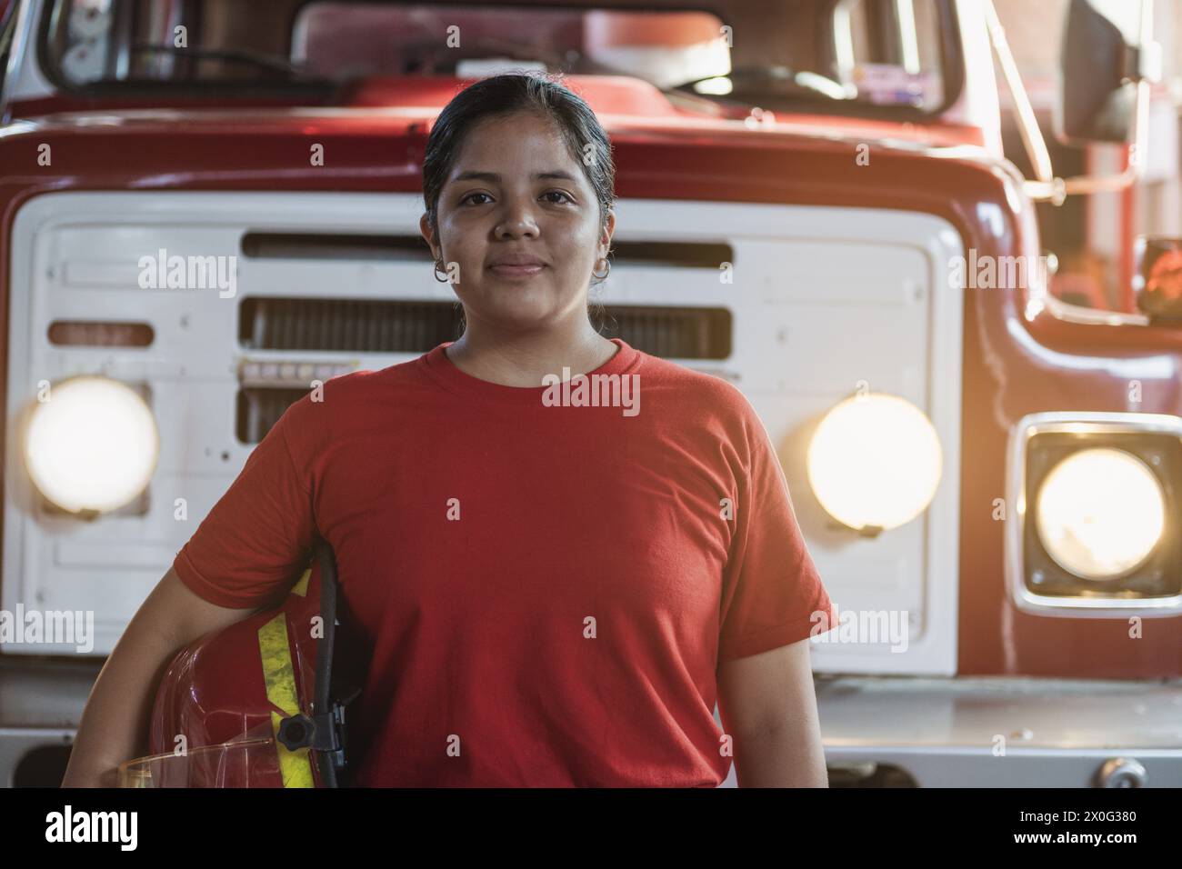 Portrait of smiling female firefighter standing at the fire station ...