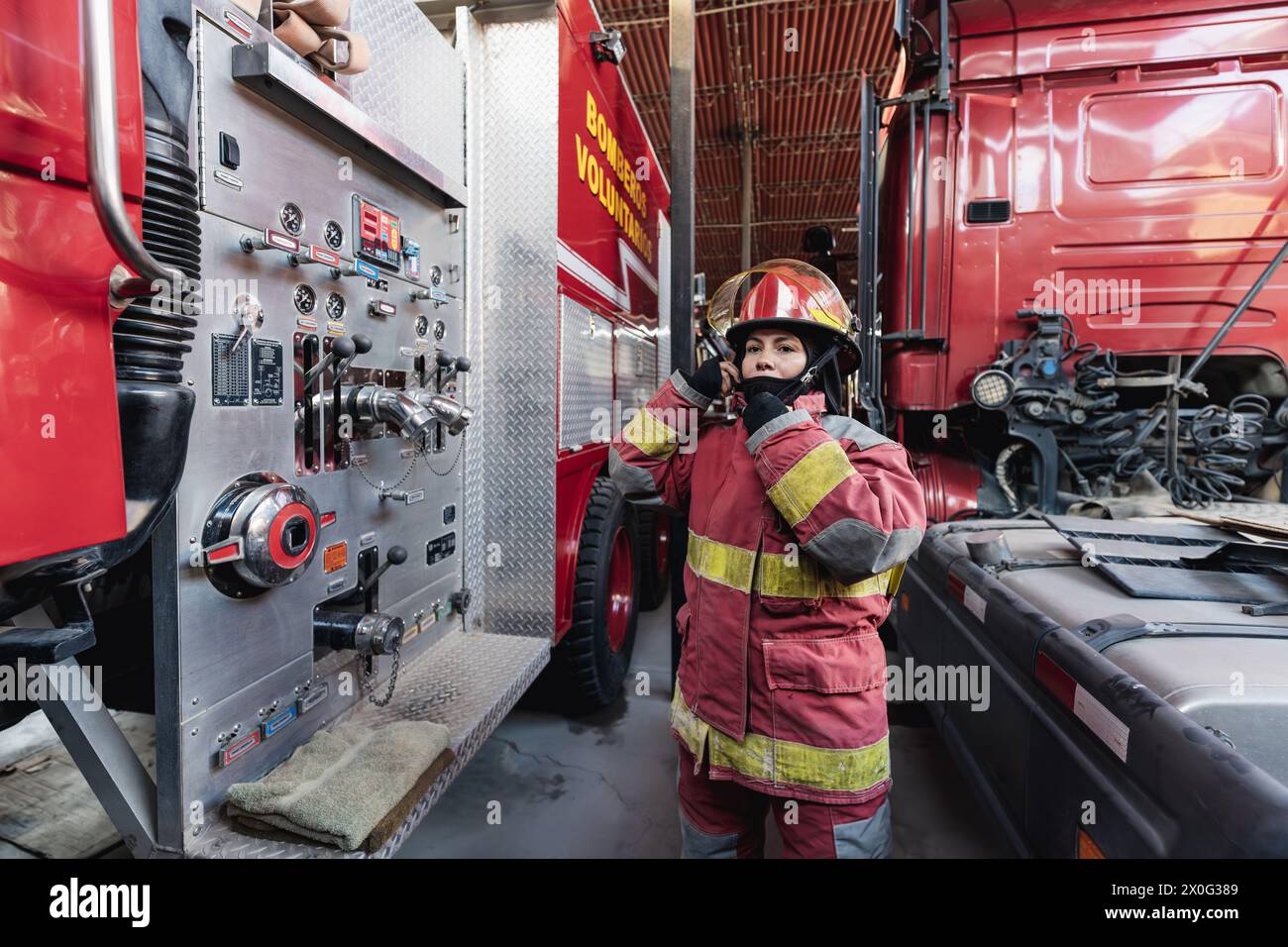 Female Firefighter In Fire Protection Suit standing at fire station ...