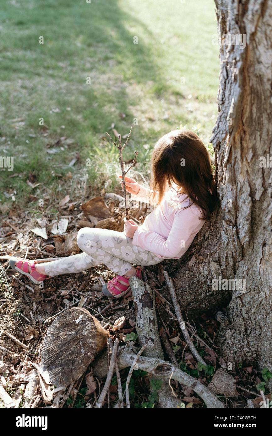 little girl sitting under a tree enjoying nature Stock Photo - Alamy