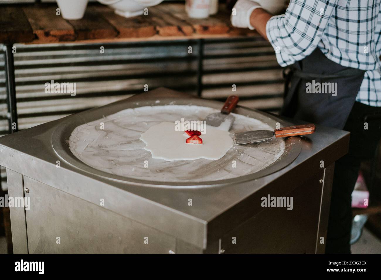 Halved strawberry in milk on frozen rolled ice cream machine Stock ...