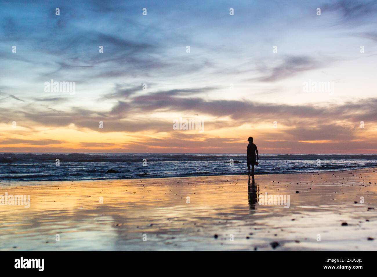 Young boy exploring at blue hour on the beach Stock Photo - Alamy