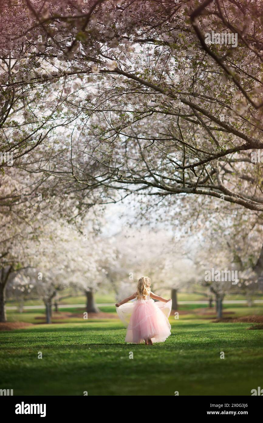 A child twirls under a canopy of cherry blossoms, immersed in wonder ...