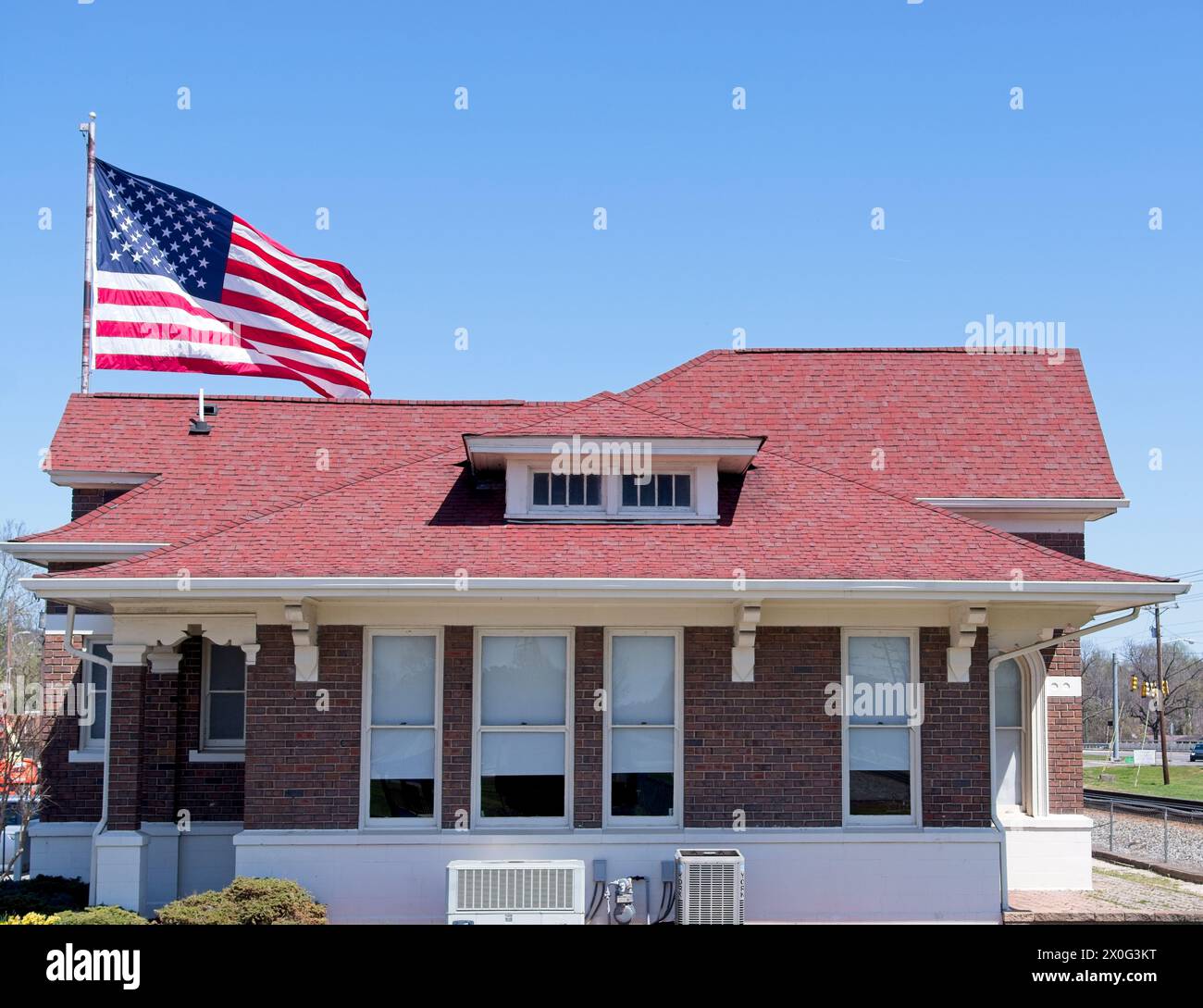 American flag flying over a building with a red shingled roof with ...