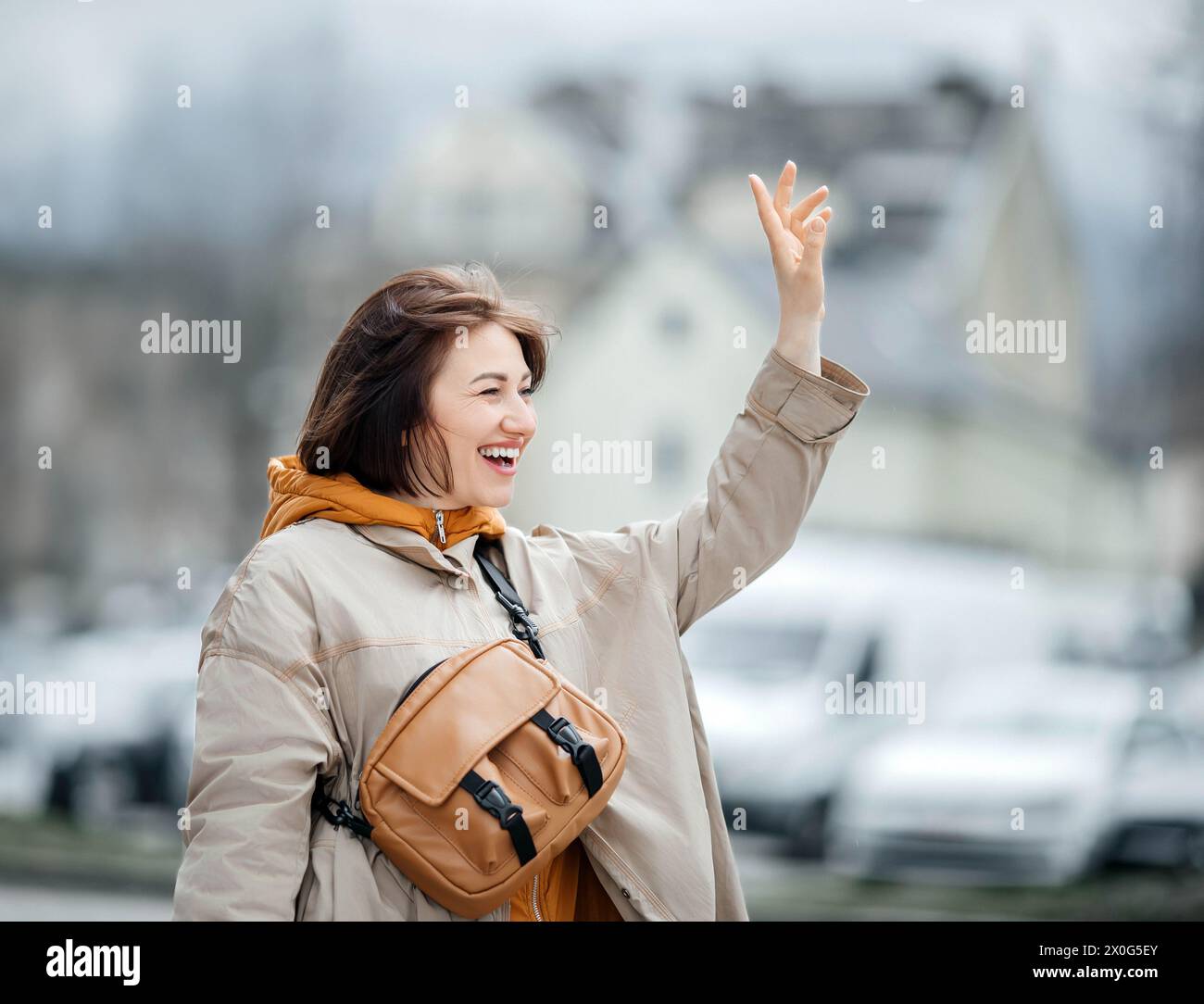 Cheerful Woman Greeting Someone Outdoors with a Waving Hand Stock Photo ...