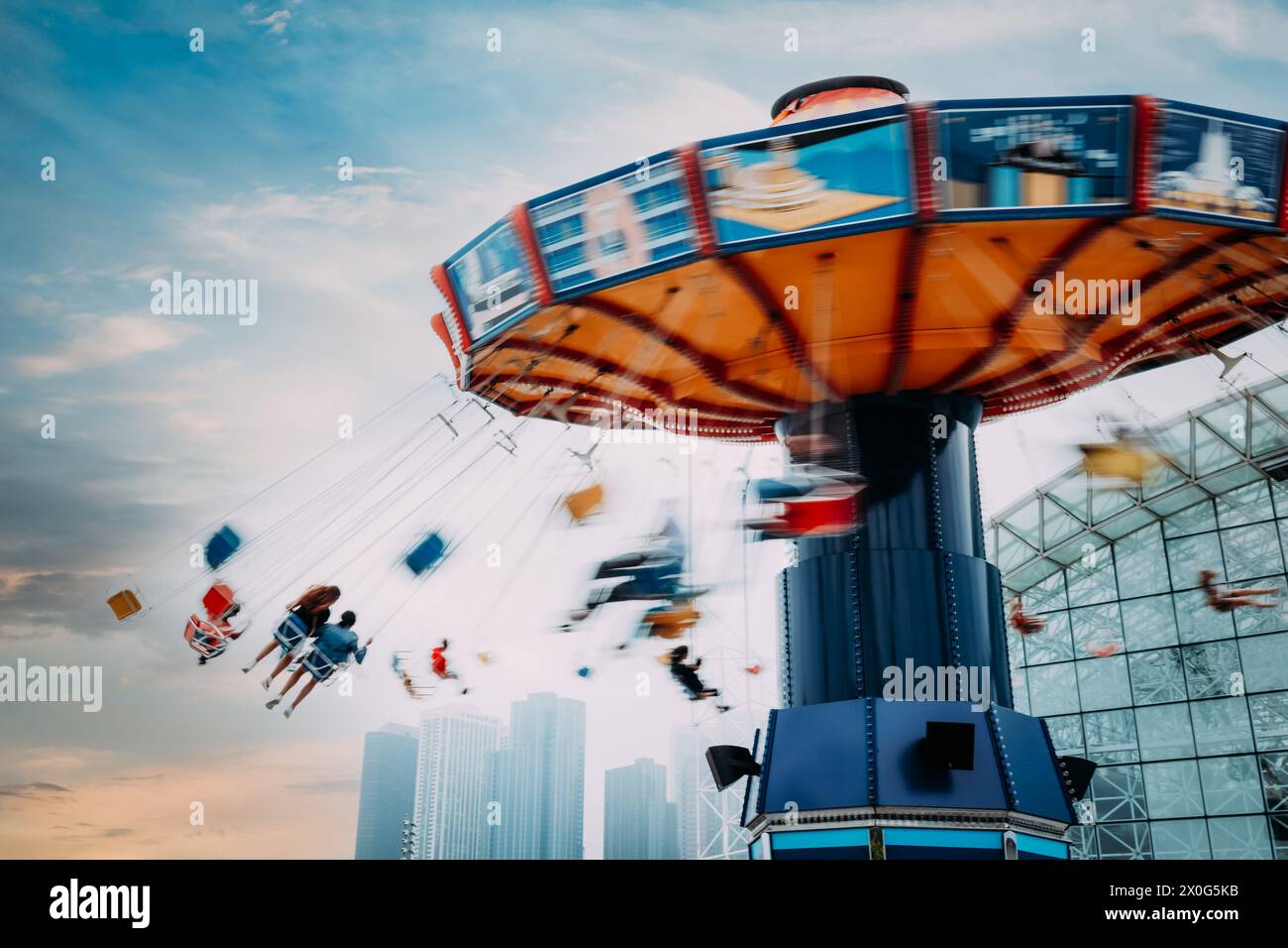Colorful carnival swing ride with cityscape in background Stock Photo ...