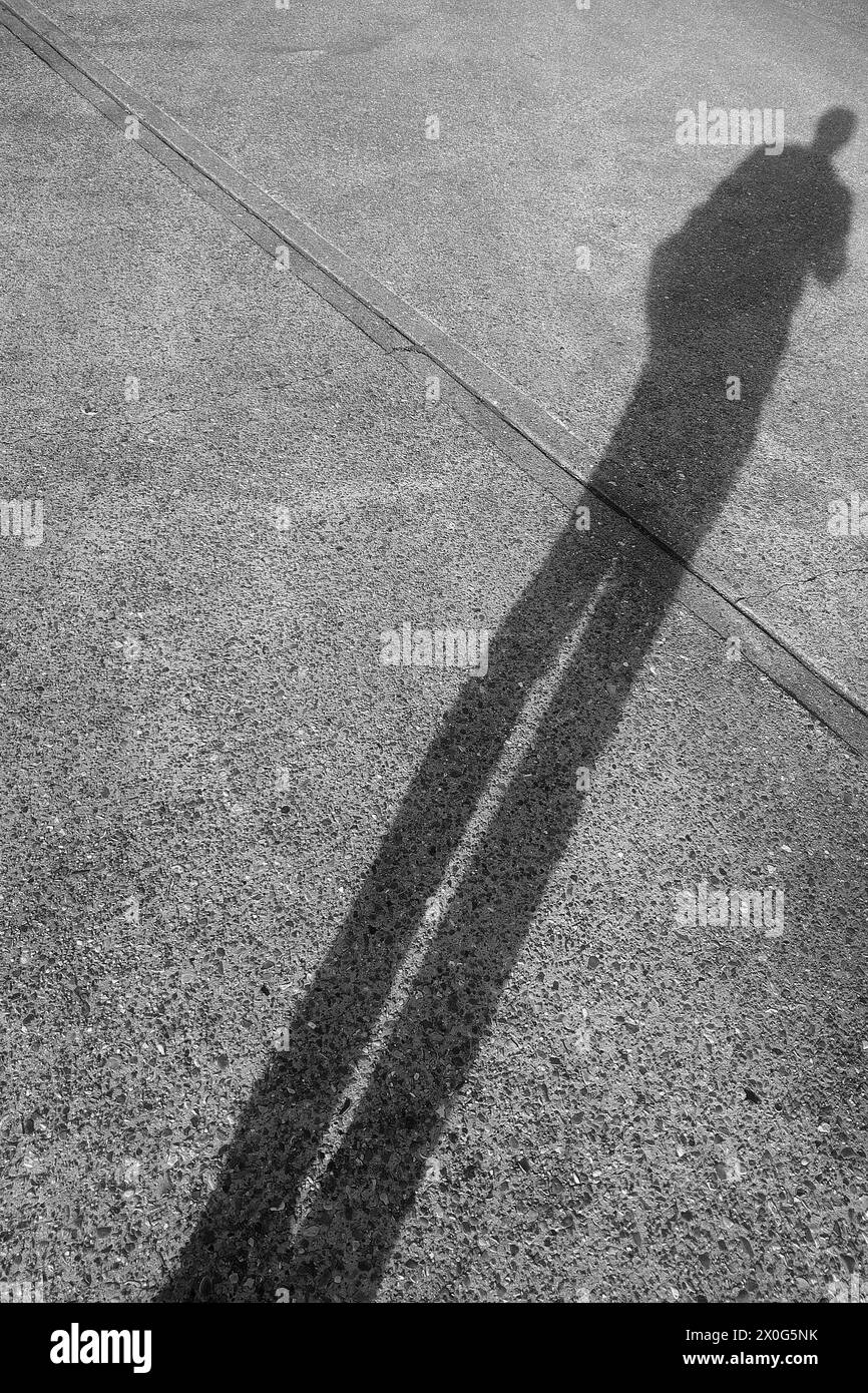 Elongated shadow of myself crossing over a drainage line in London, UK ...