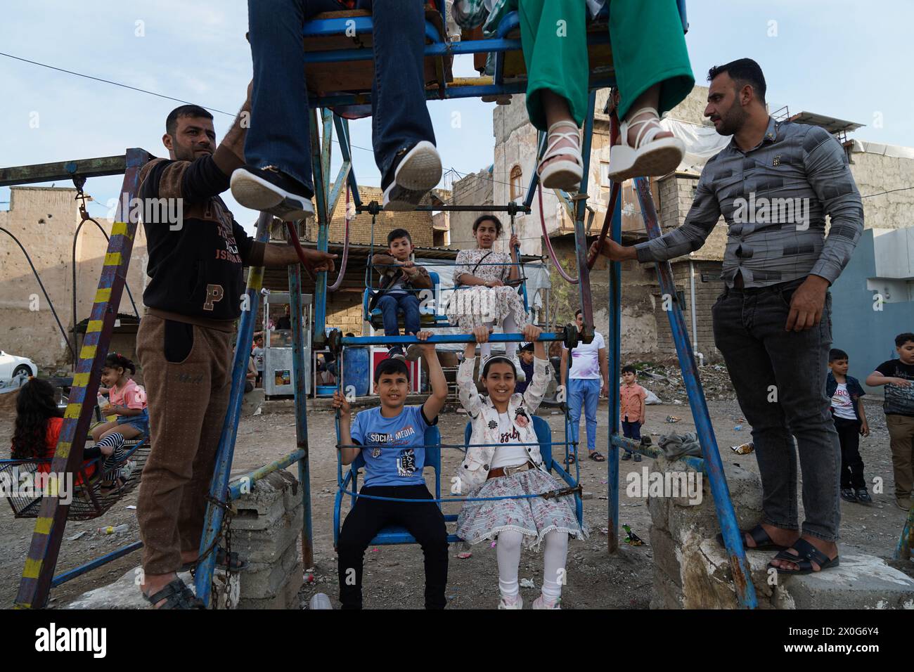 Iraqi children play on a hand-powered ferris wheel at a mobile ...