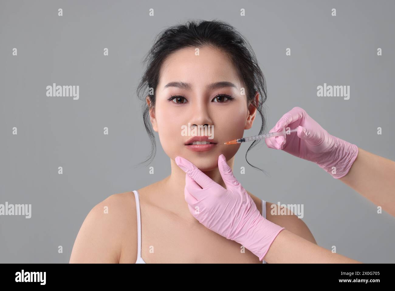 Woman getting lip injection on grey background Stock Photo - Alamy