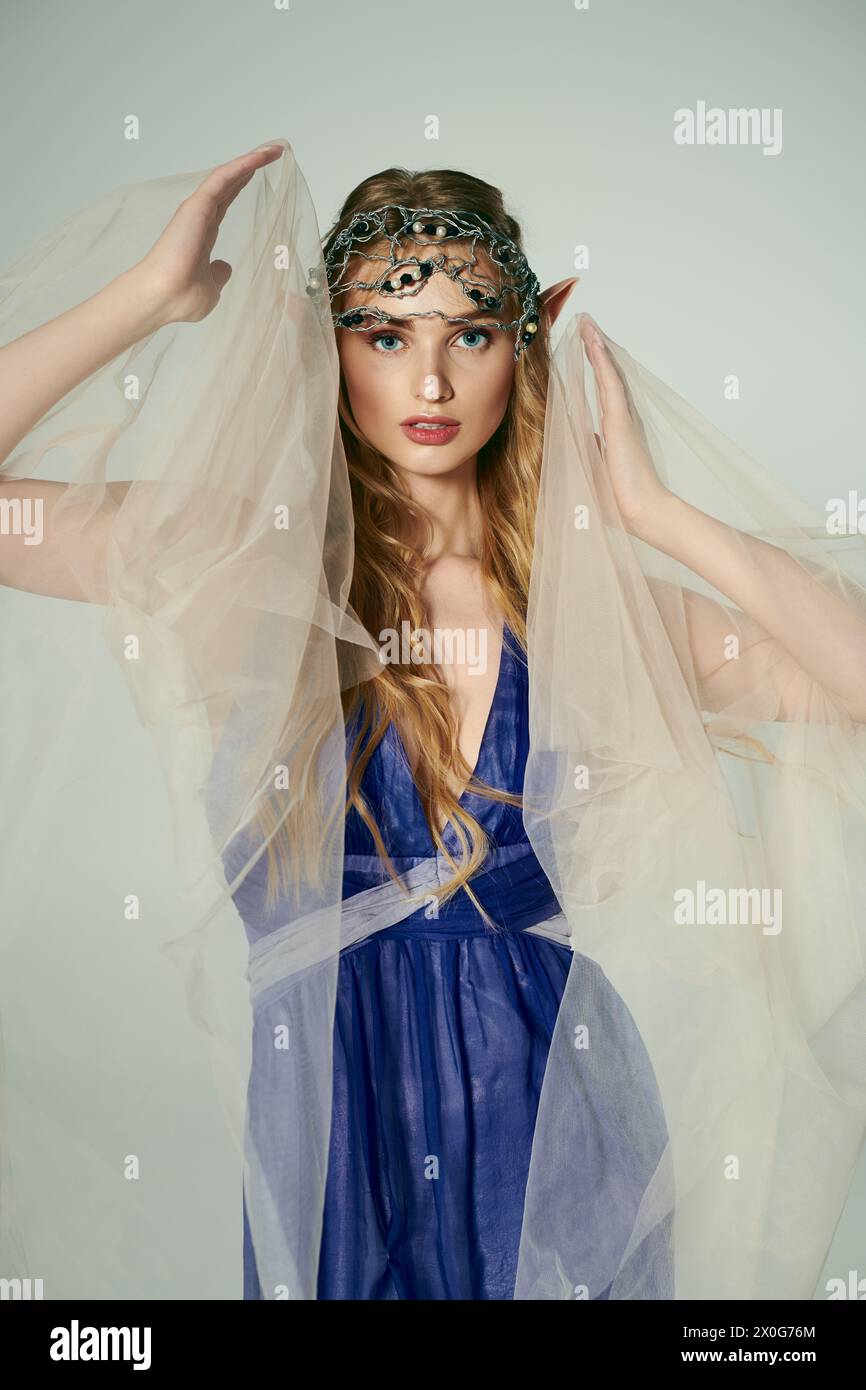A young woman exudes elegance in a blue dress with a delicate veil over ...