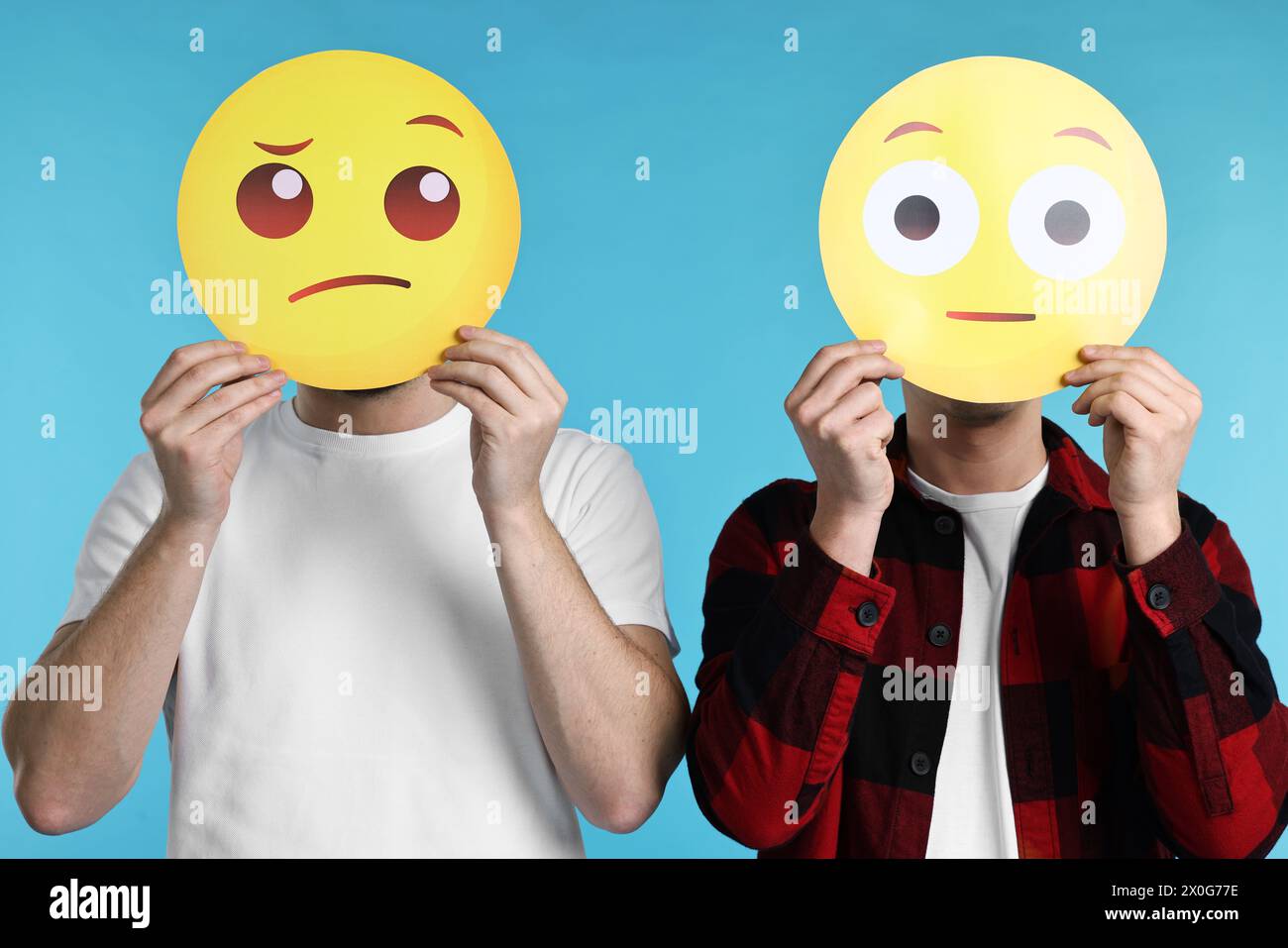 People covering faces with emoticons on light blue background Stock ...