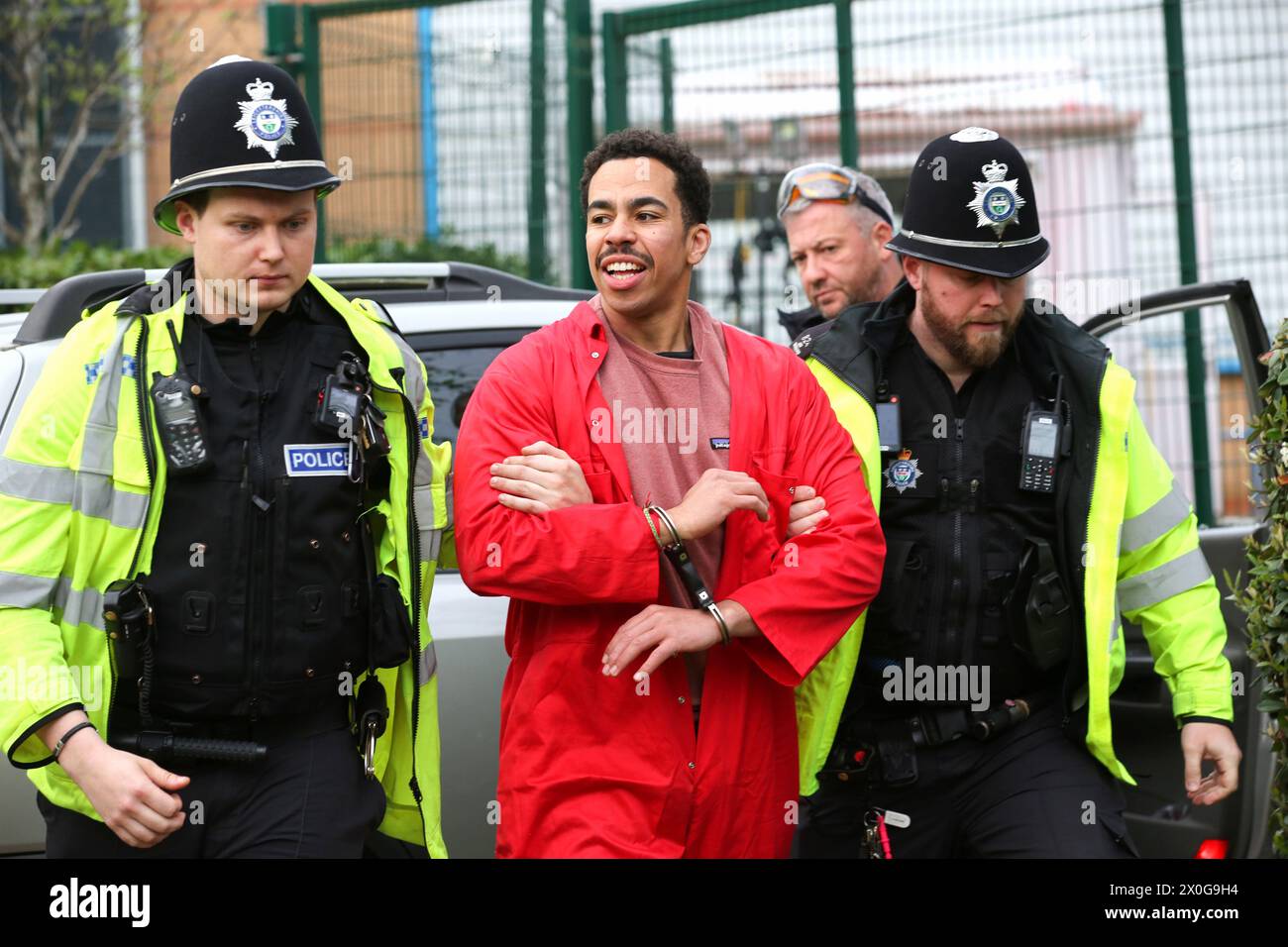An activist wearing the red jumpsuit of Palestine Action is led away in ...