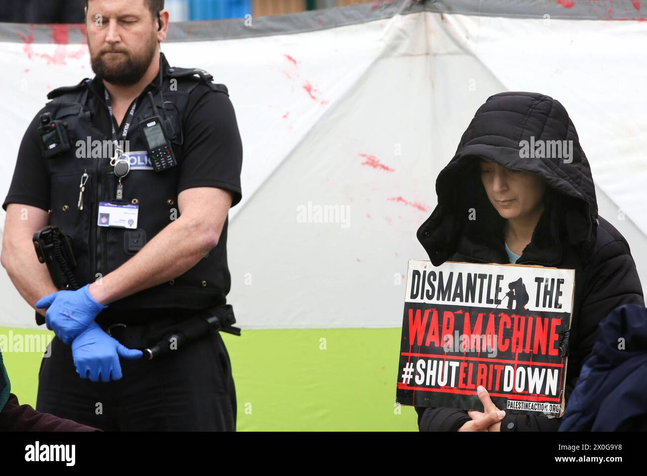 A protester stands holding a sign that says "Dismantle The War Machine ...