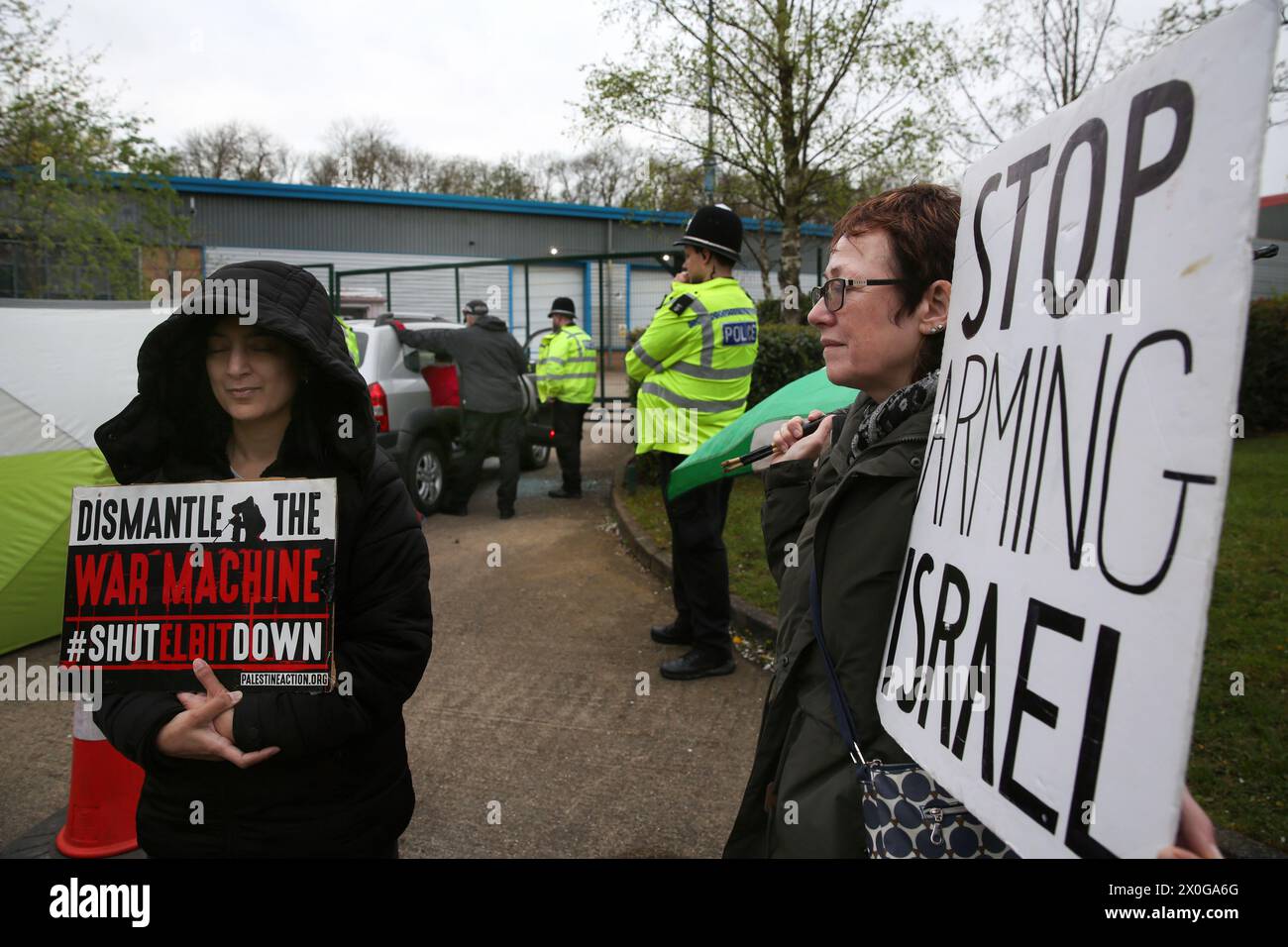 Protesters stand holding signs that say "Stop Arming Israel" and ...