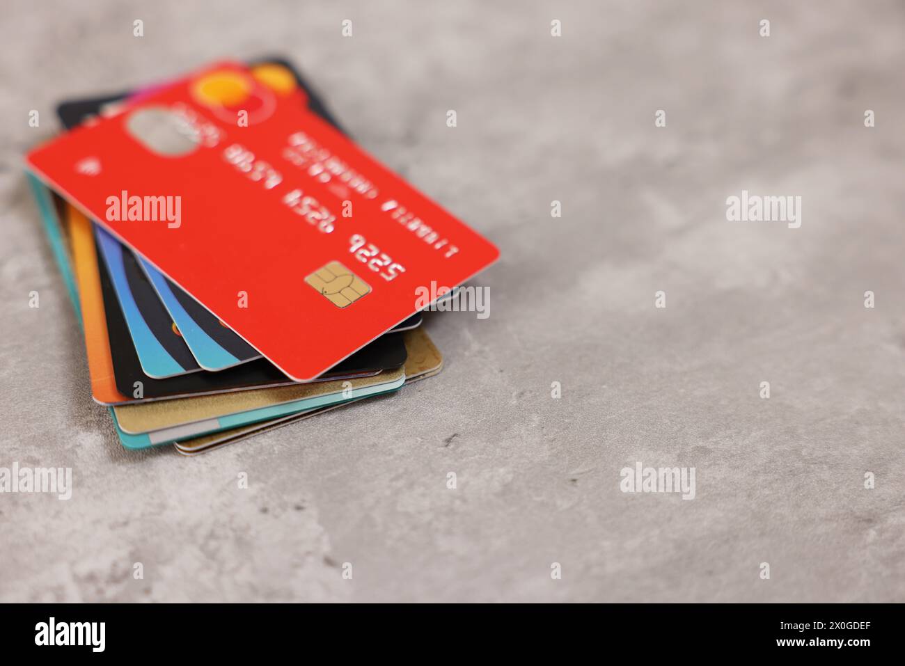 Pile of different credit cards on grey table, closeup. Space for text ...