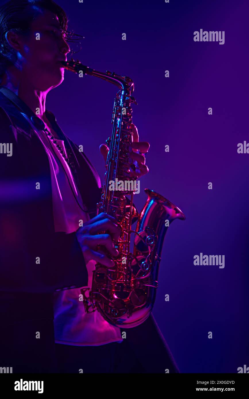 Portrait of young attractive man in dark suit playing saxophone in ...