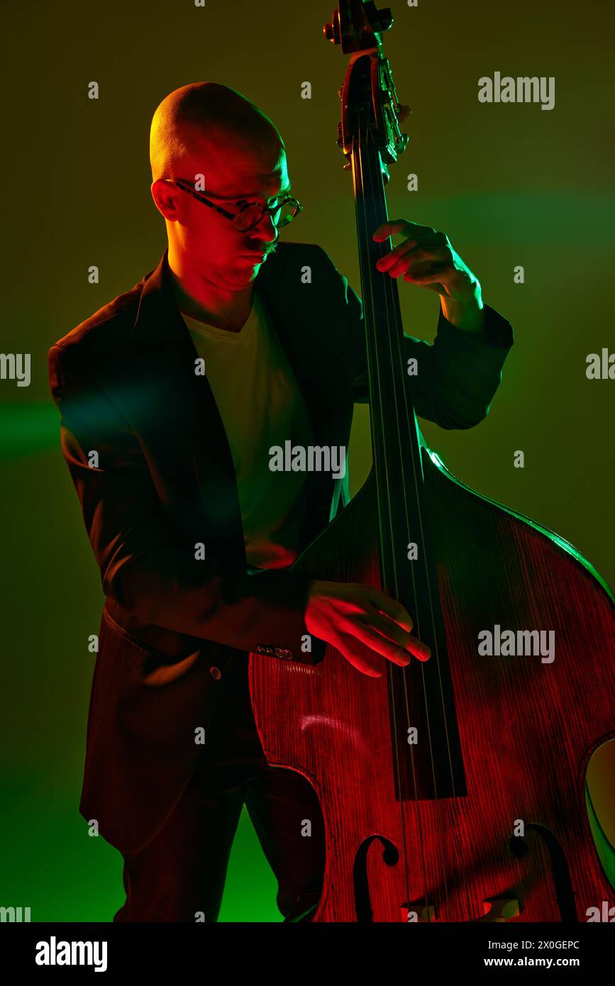 Portrait of bald musician in glasses plays double bass in red-green ...