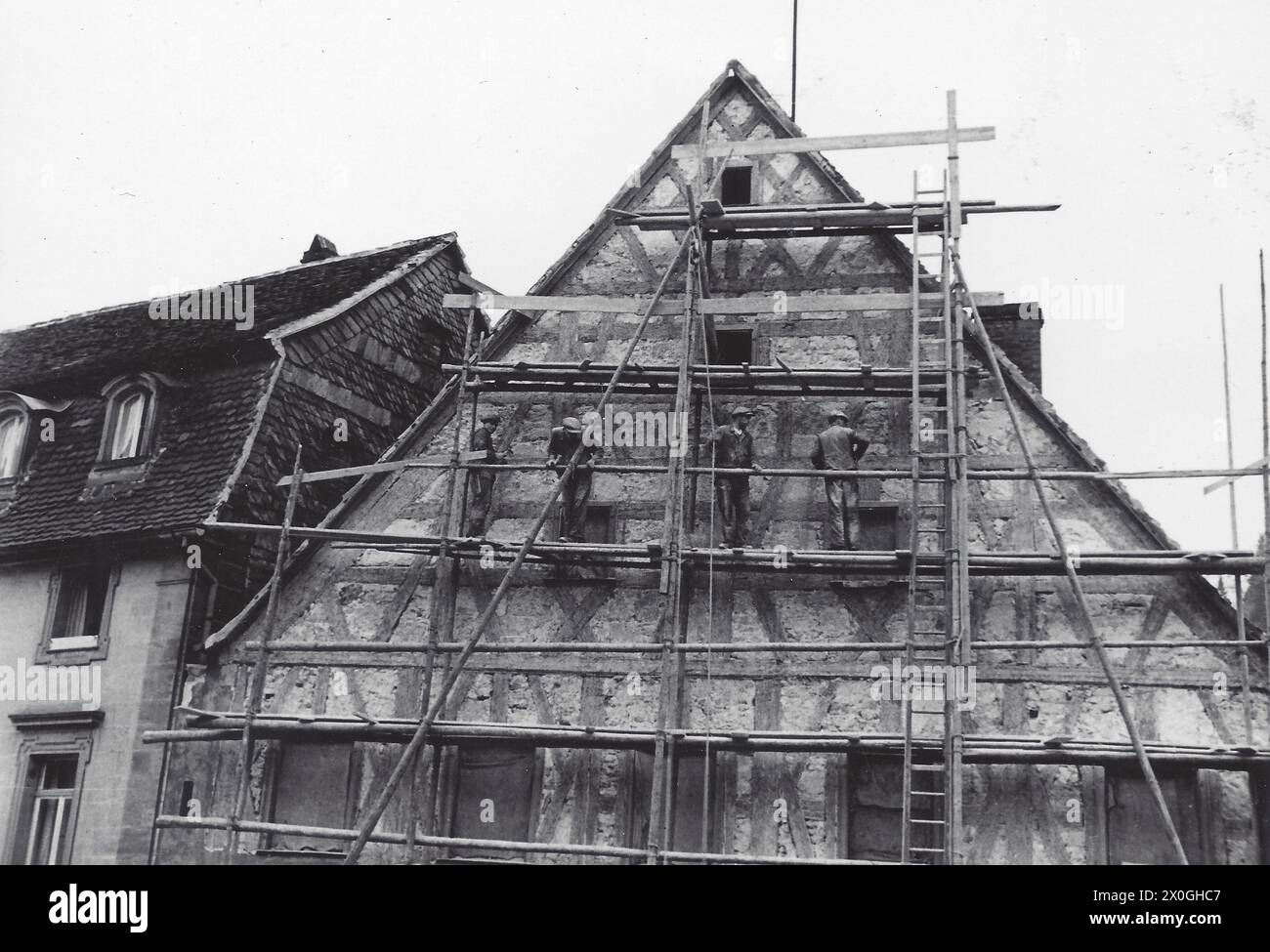 Four bricklayers stand on a scaffold at the new construction of a half ...