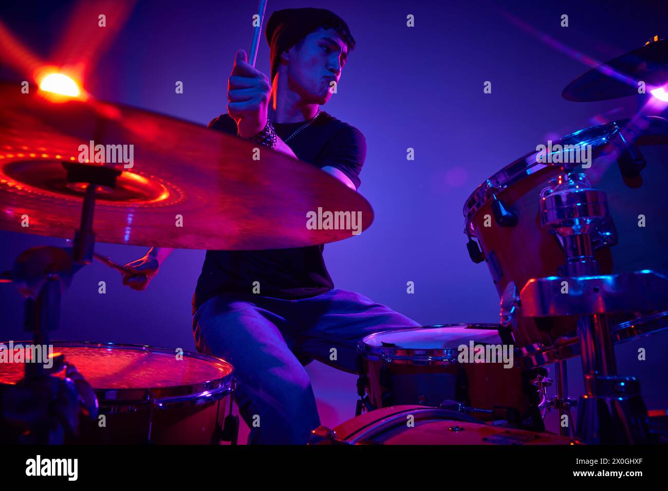 Drummer in casual attire practices with serious expression in pink ...