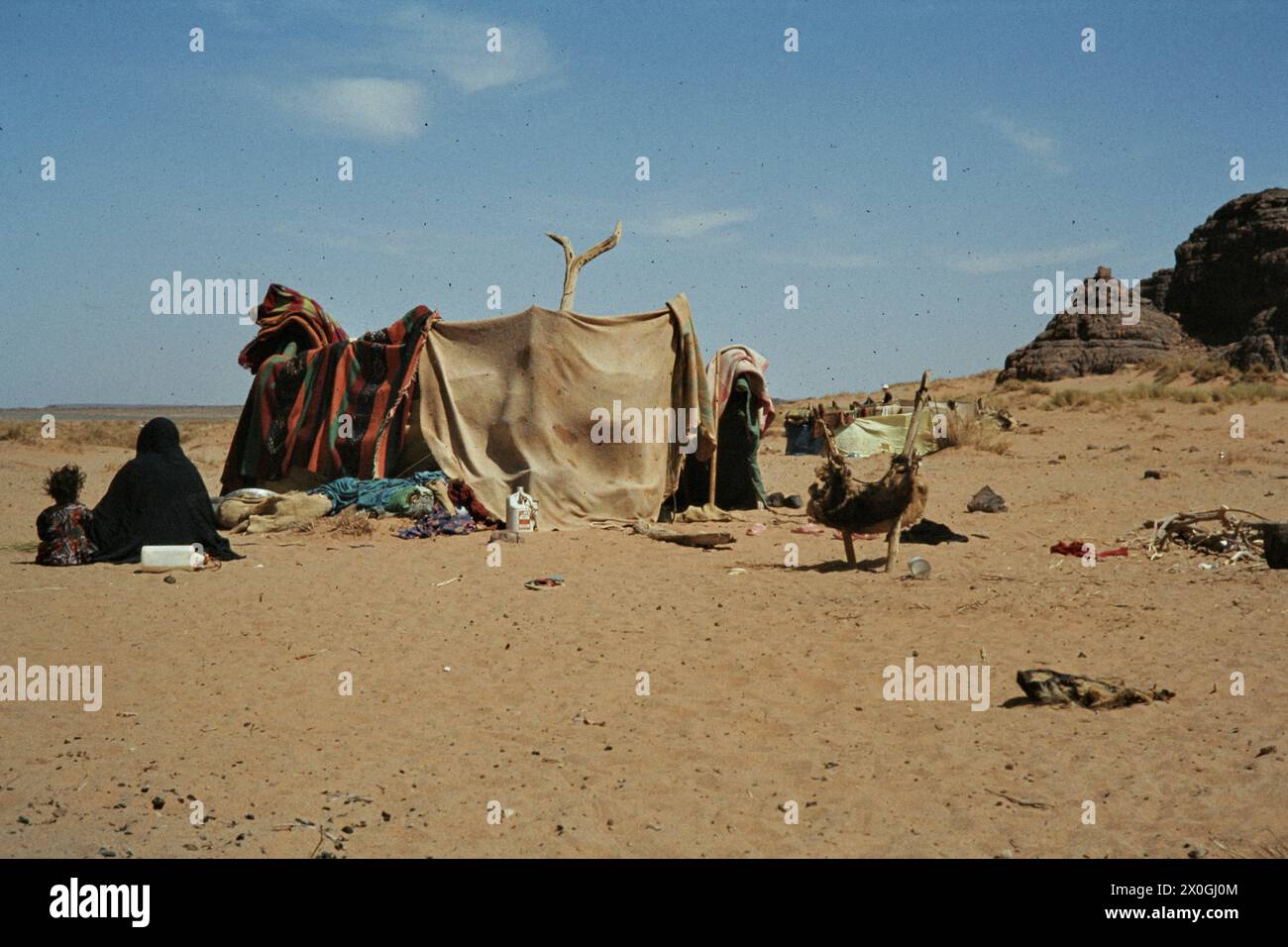 Targia mother and child are sitting in the sand in front of their ...