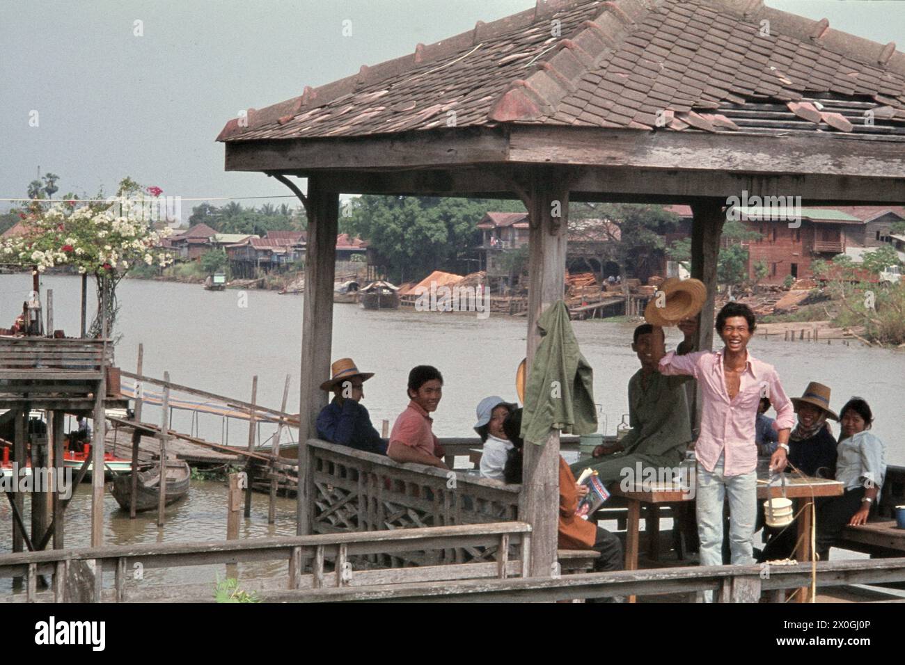 A group of locals is sitting around a table with a view of the Mae Nam ...