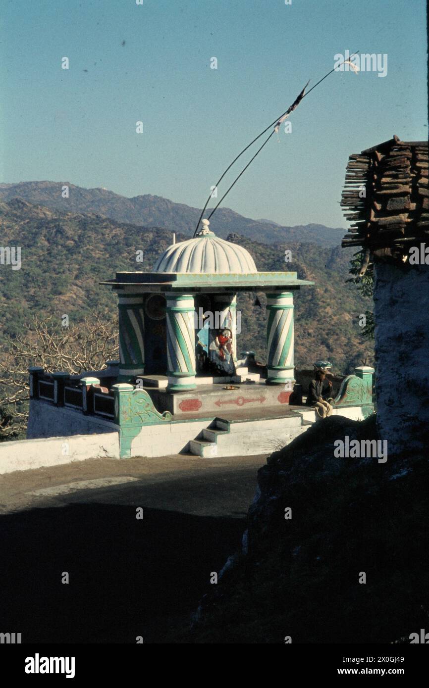 A man is sitting on the steps of a small Hanuman temple in the ...