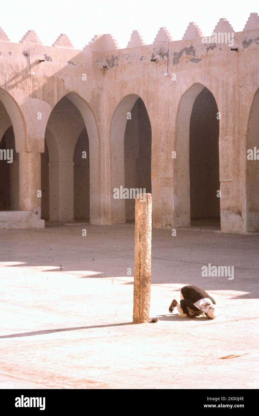 Praying Muslim in front of the arcades in the courtyard of the ...
