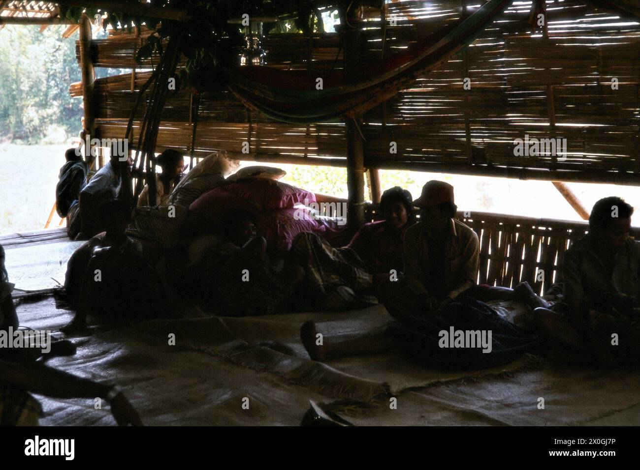 Funeral participants wait in a dark hut for the ceremony to begin ...