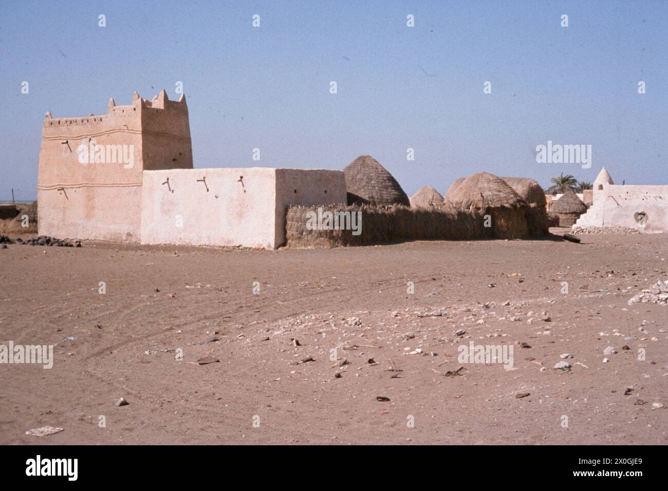 A walled house in the middle of simple huts in the Yemeni village of al ...