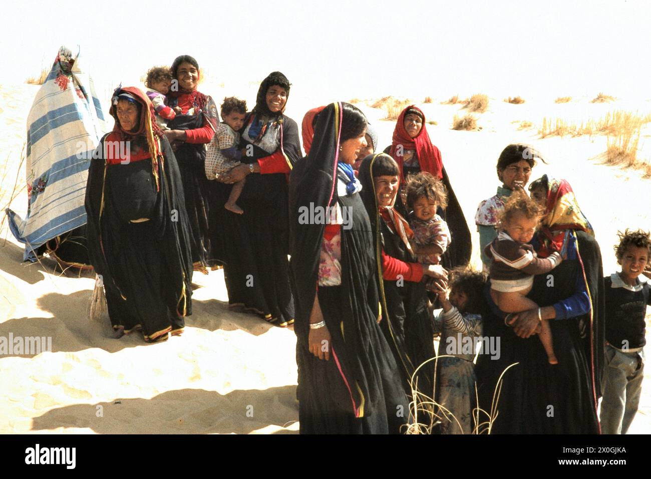Several Bedouin women in uniform black clothing with their children in ...