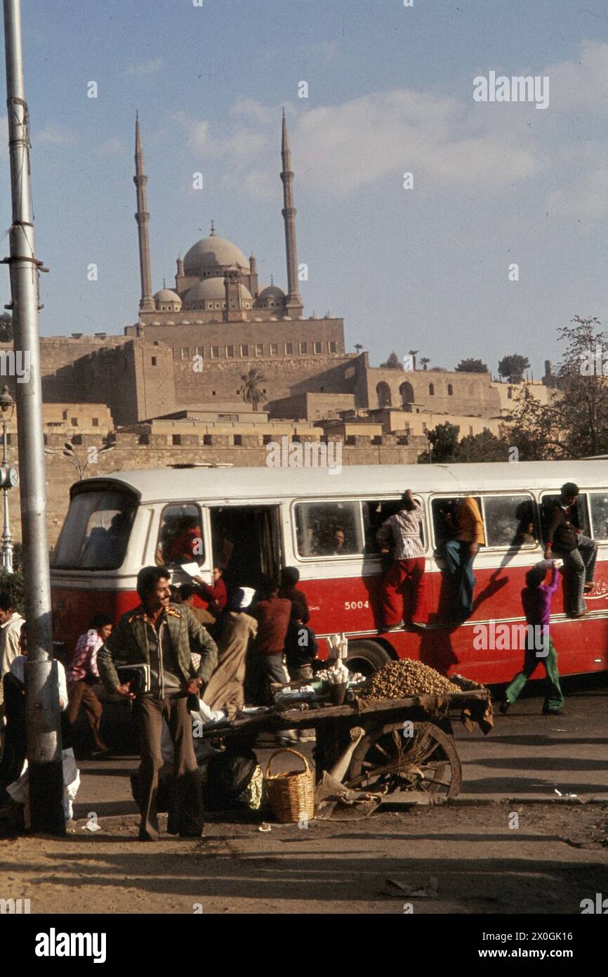 An overcrowded bus is in front of the Citadel of Saladin in the center ...