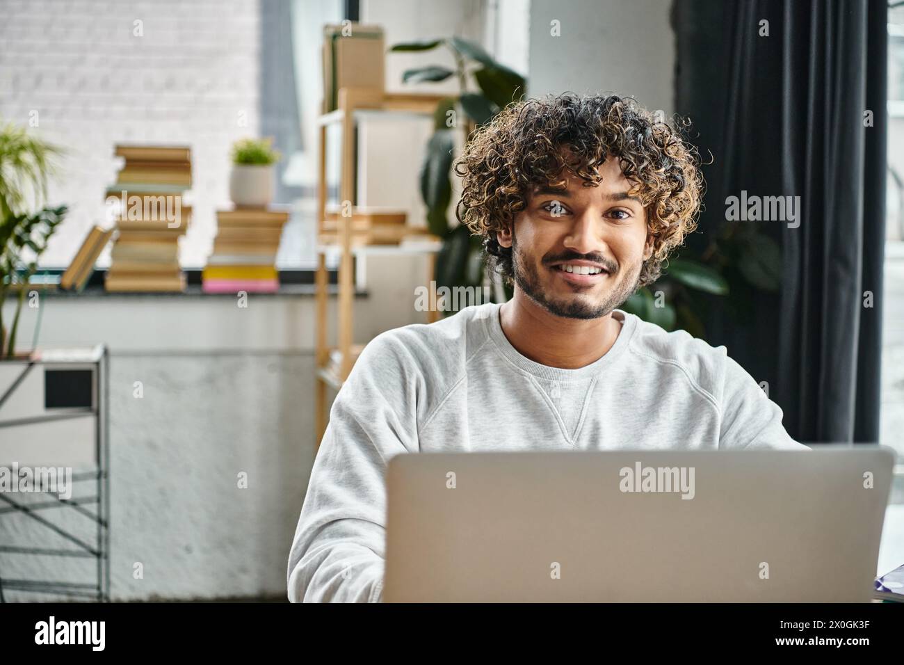 A man of diverse background sits engrossed in his laptop, exploring the ...