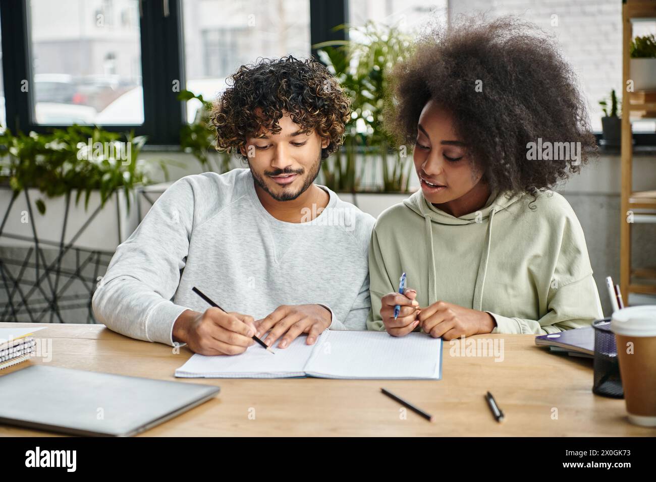 A man and a woman of different ethnic backgrounds sit at a table ...