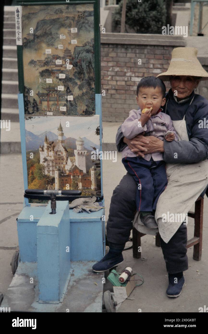 An elderly woman with a child on her lap is sitting next to a play ...