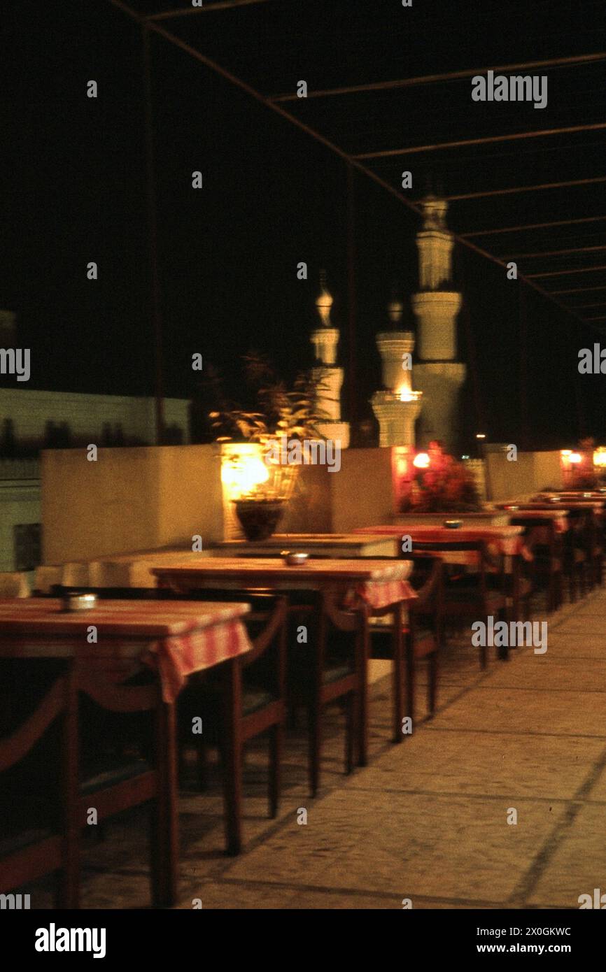Tables on the roof terrace of the Hussein Hotel with the illuminated Al ...