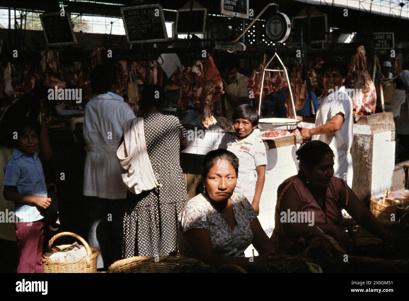 People buy meat from a butcher at a market in Piura. [automated ...