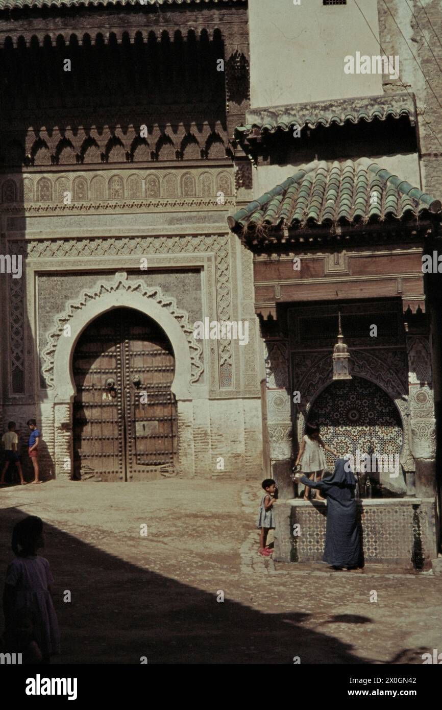 A mother with children at a well at Placa Nejjarine in Fez. [automated ...