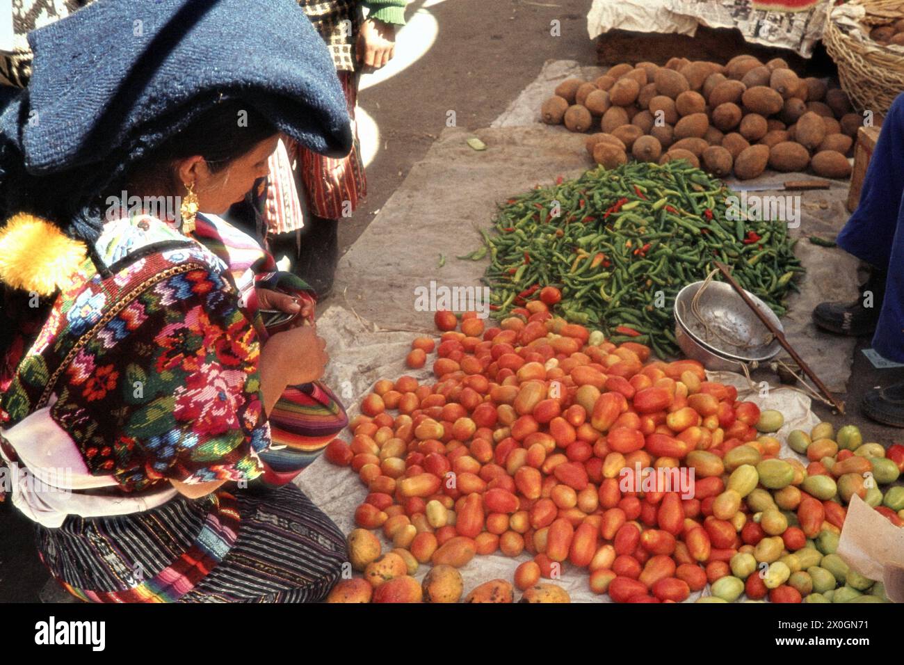 A woman in traditional costume sells vegetables at a market place in ...