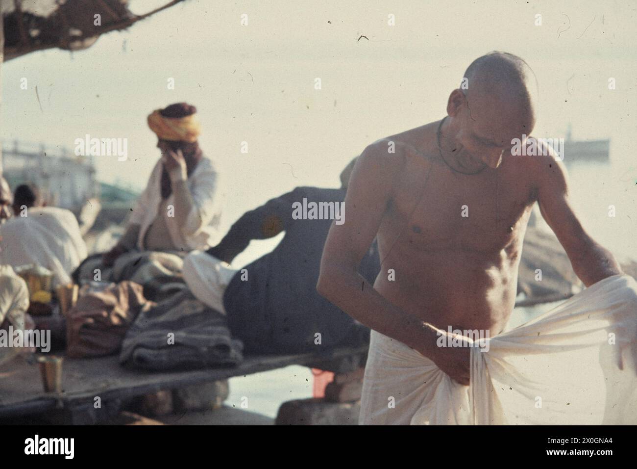 A man cleans his clothes at the ghats of the Ganges in Varanasi ...
