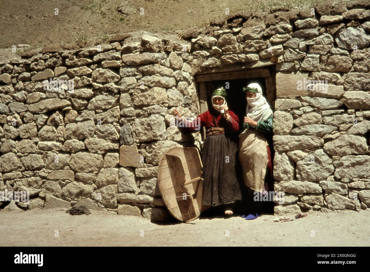 Turkish women in traditional dress stand in the entrance of a hut in a ...