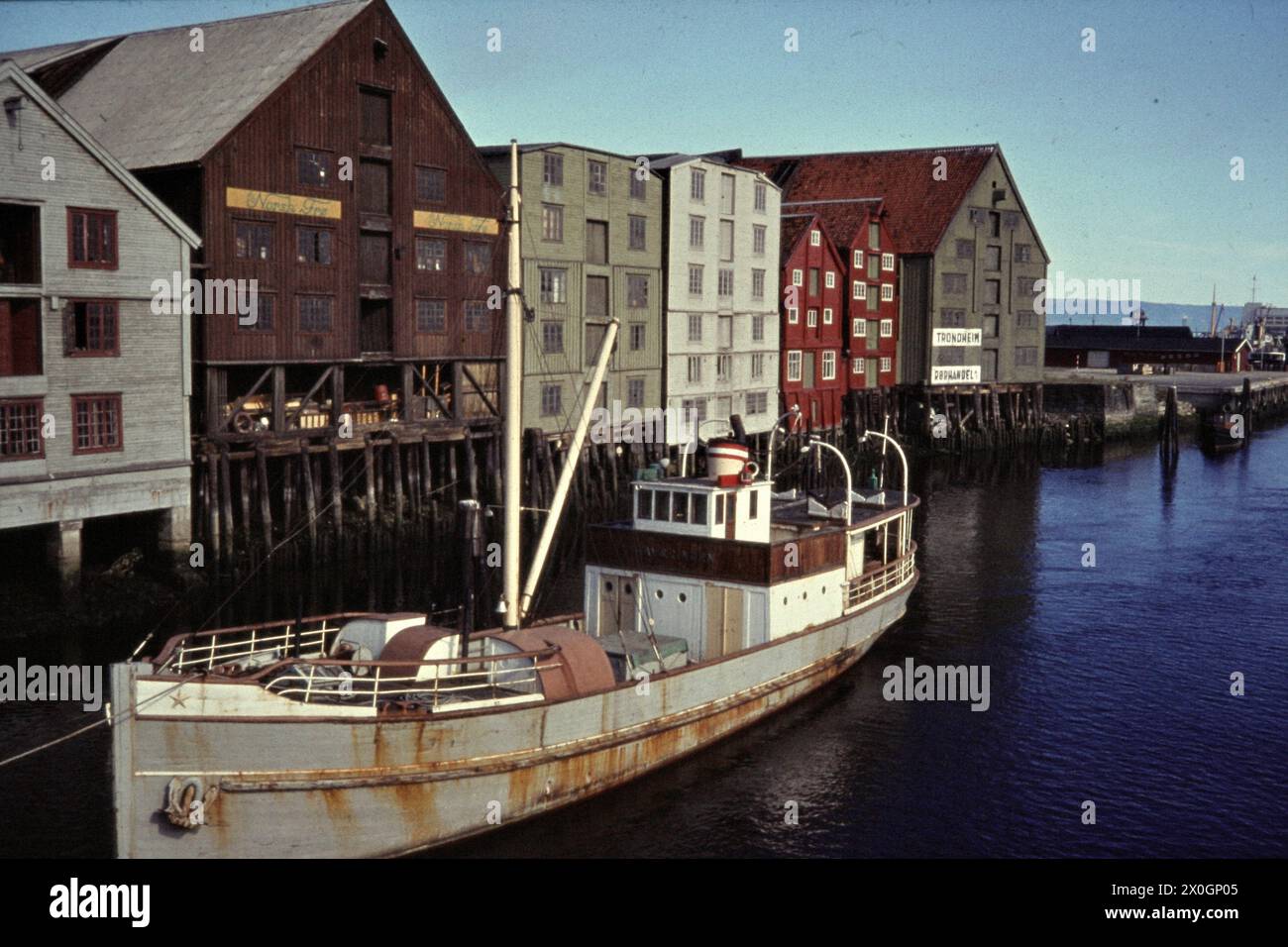 A fishing boat on the Nidelv river in front of old warehouses in the ...