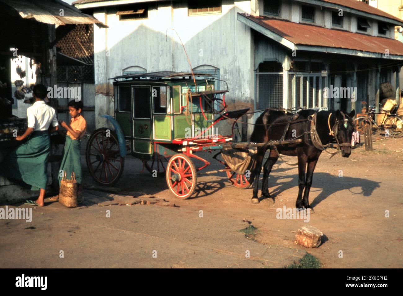Two boys stand next to an old-fashioned carriage and draught horse ...