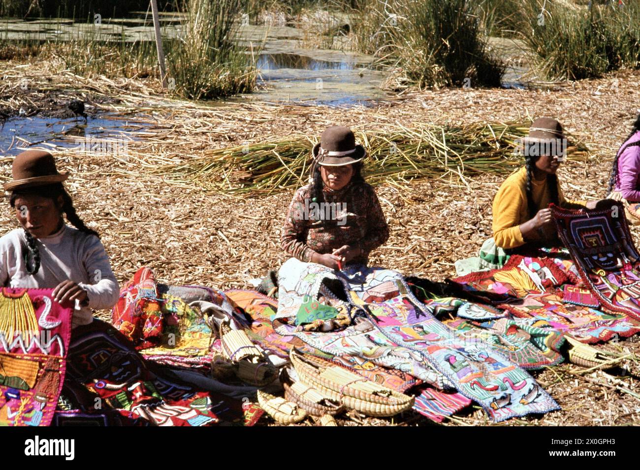 Women sitting on the ground in traditional costume sell woven goods at ...