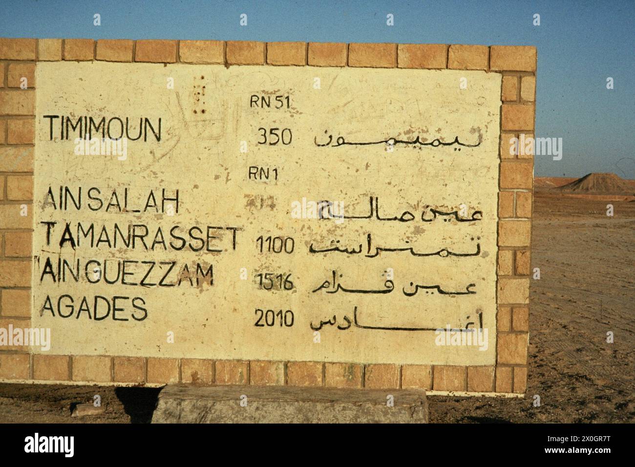 A stone sign indicating the distance to Timimoun, Ainsalah, Tamanrasset ...