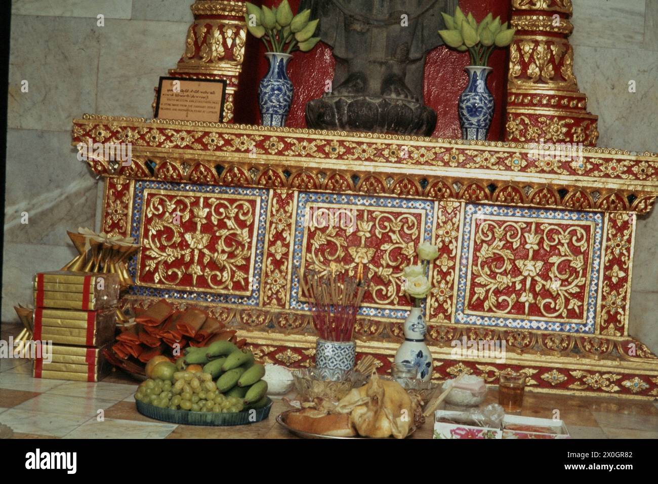 Food offerings, like fruit and pastries, in front of an altar in ...
