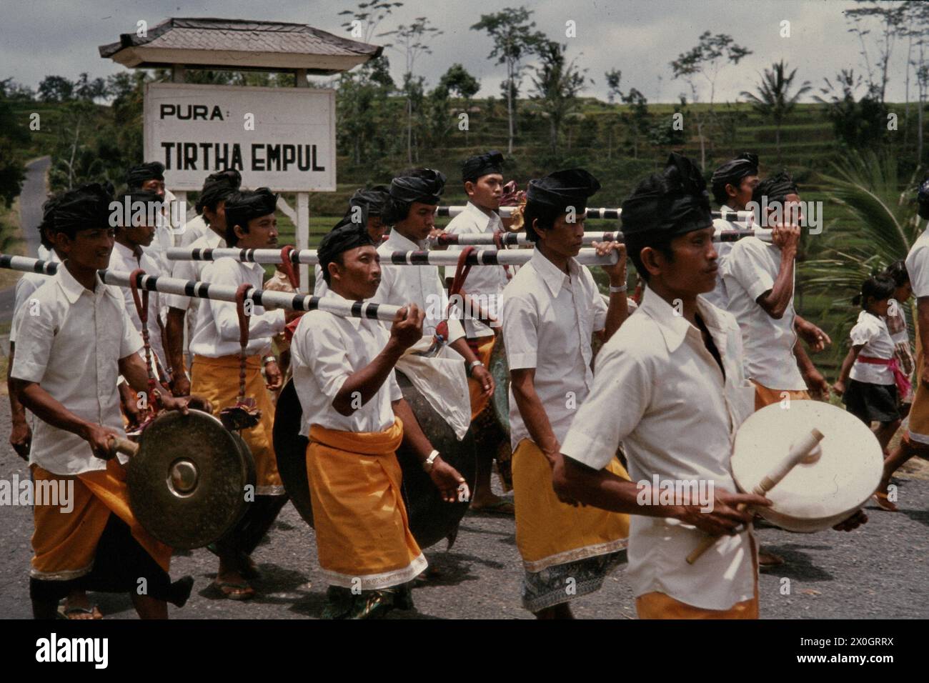 A band with uniform clothing and traditional instruments marches down a ...