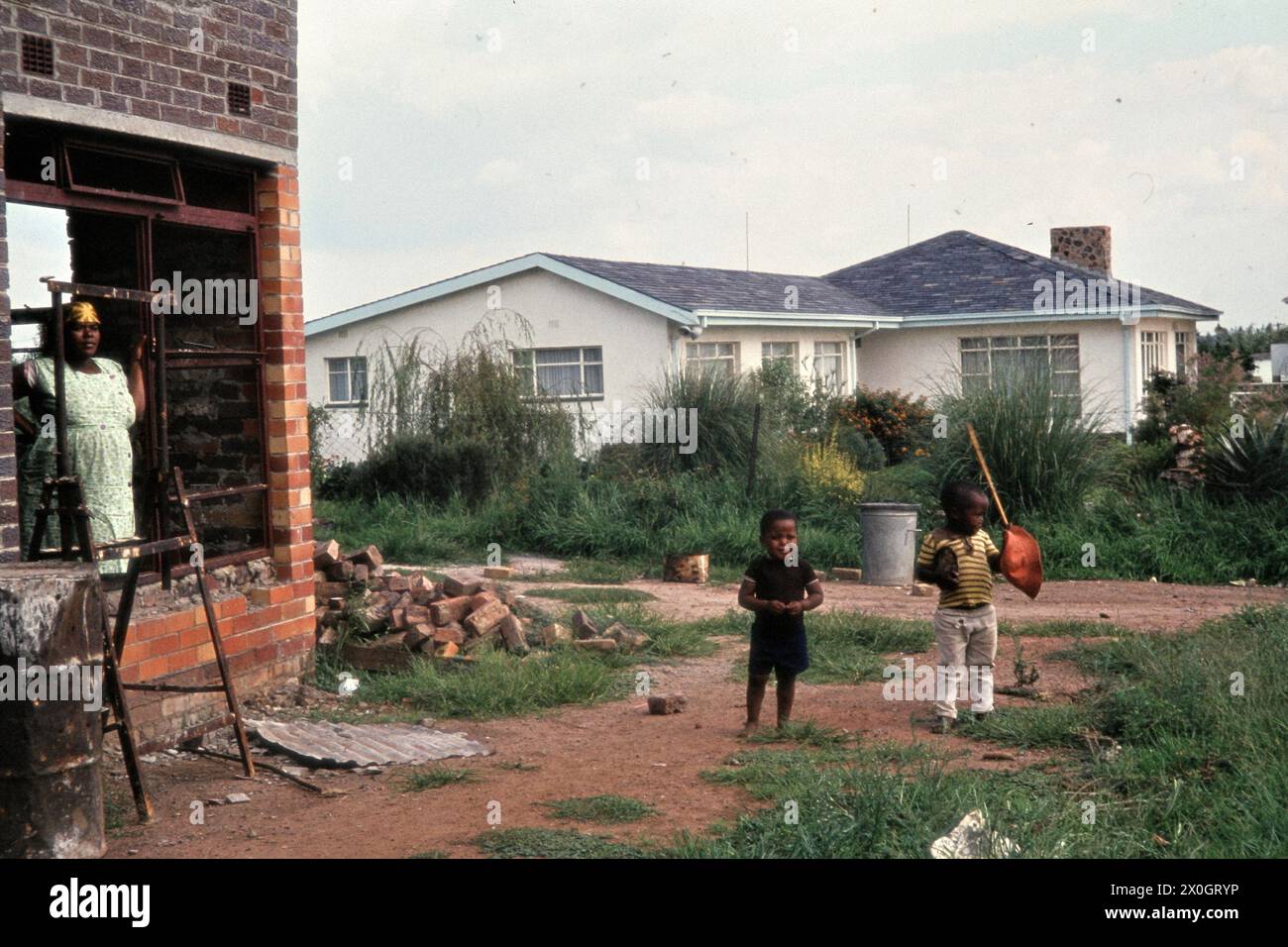 "A woman with two children in front of the ""house of one of the three ...