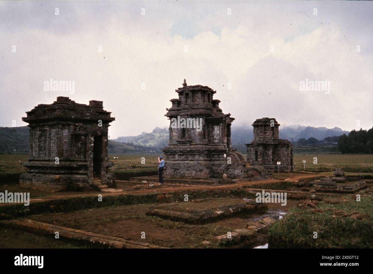 A tourist stands in front of the ruins of Candi Dieng on the Dieng ...